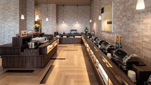 Disposição de buffet com várias estações de serviço, piso de madeira e paredes de tijolo.