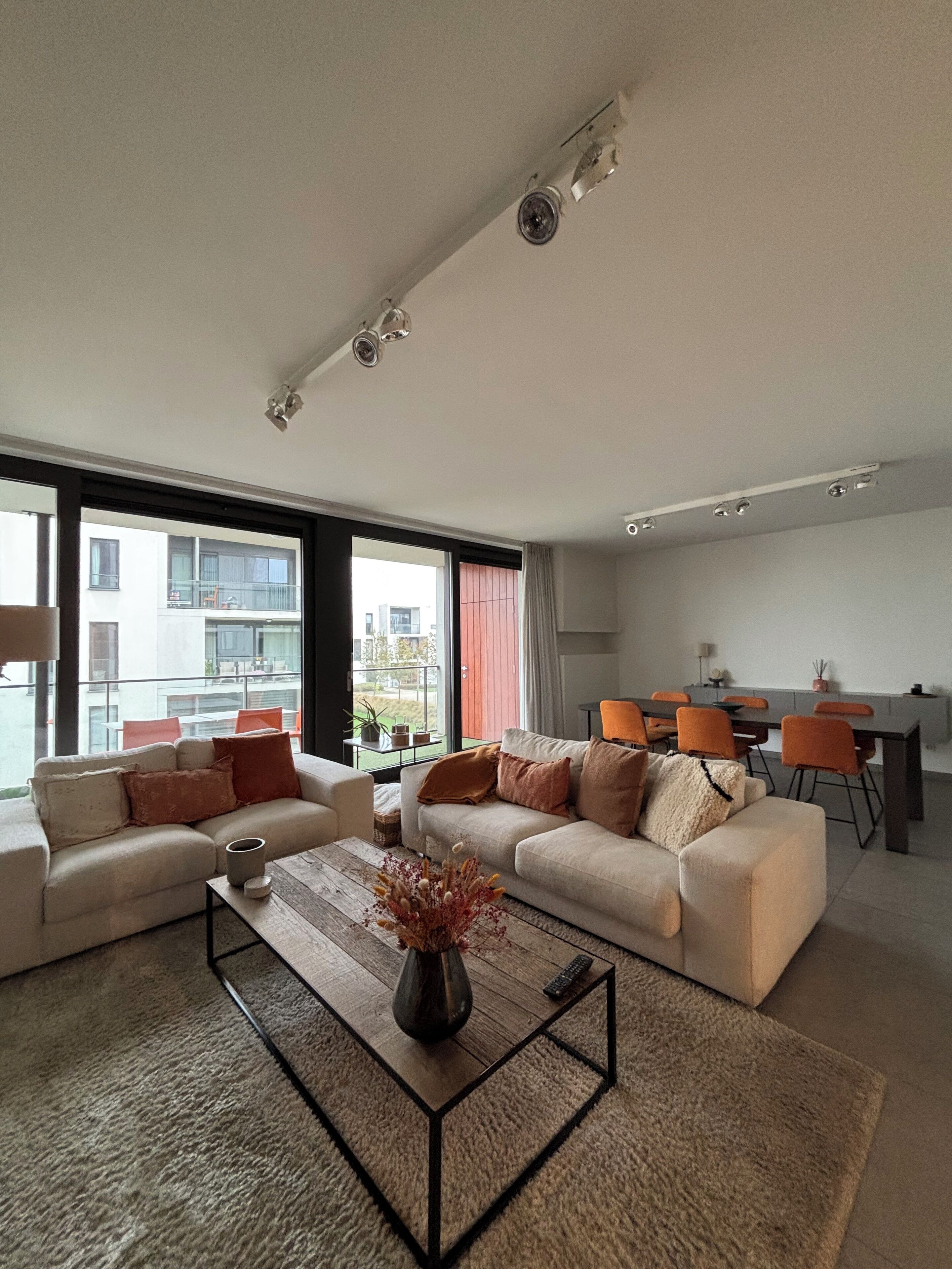 Uma sala de estar moderna com sofá, mesa de centro e área de jantar.