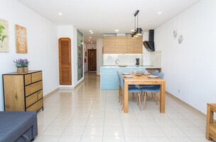 Uma cozinha moderna com armários de madeira, uma mesa de jantar com cadeiras e uma pequena mesa lateral.