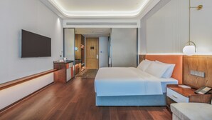 Quarto de hotel moderno com uma cama grande, mesa de cabeceira e televisão de tela plana na parede.