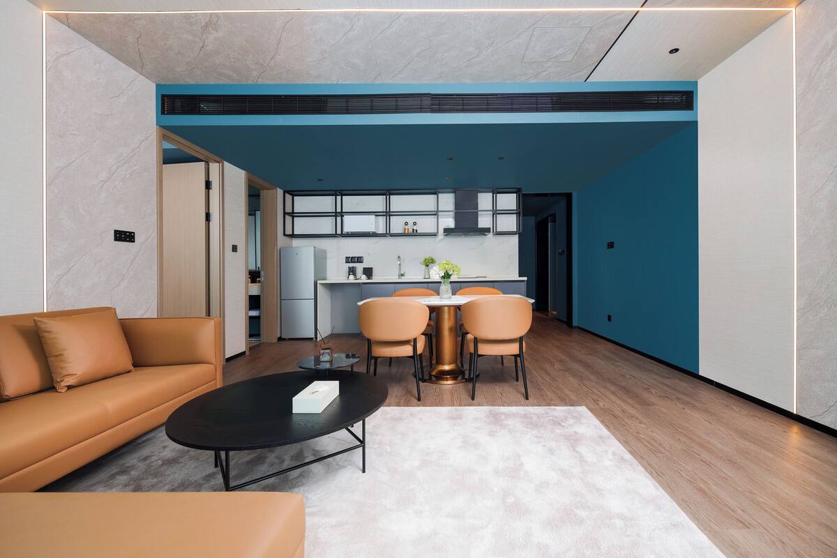 Uma sala de estar moderna com um sofá, uma mesa de centro e uma área de jantar com cadeiras e uma mesa.