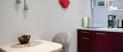 Uma cozinha moderna com bancada branca, armários vermelhos e um suporte pendurado com decorações em formato de coração.