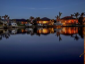 Um porto na penumbra, com águas calmas refletindo edifícios e barcos.