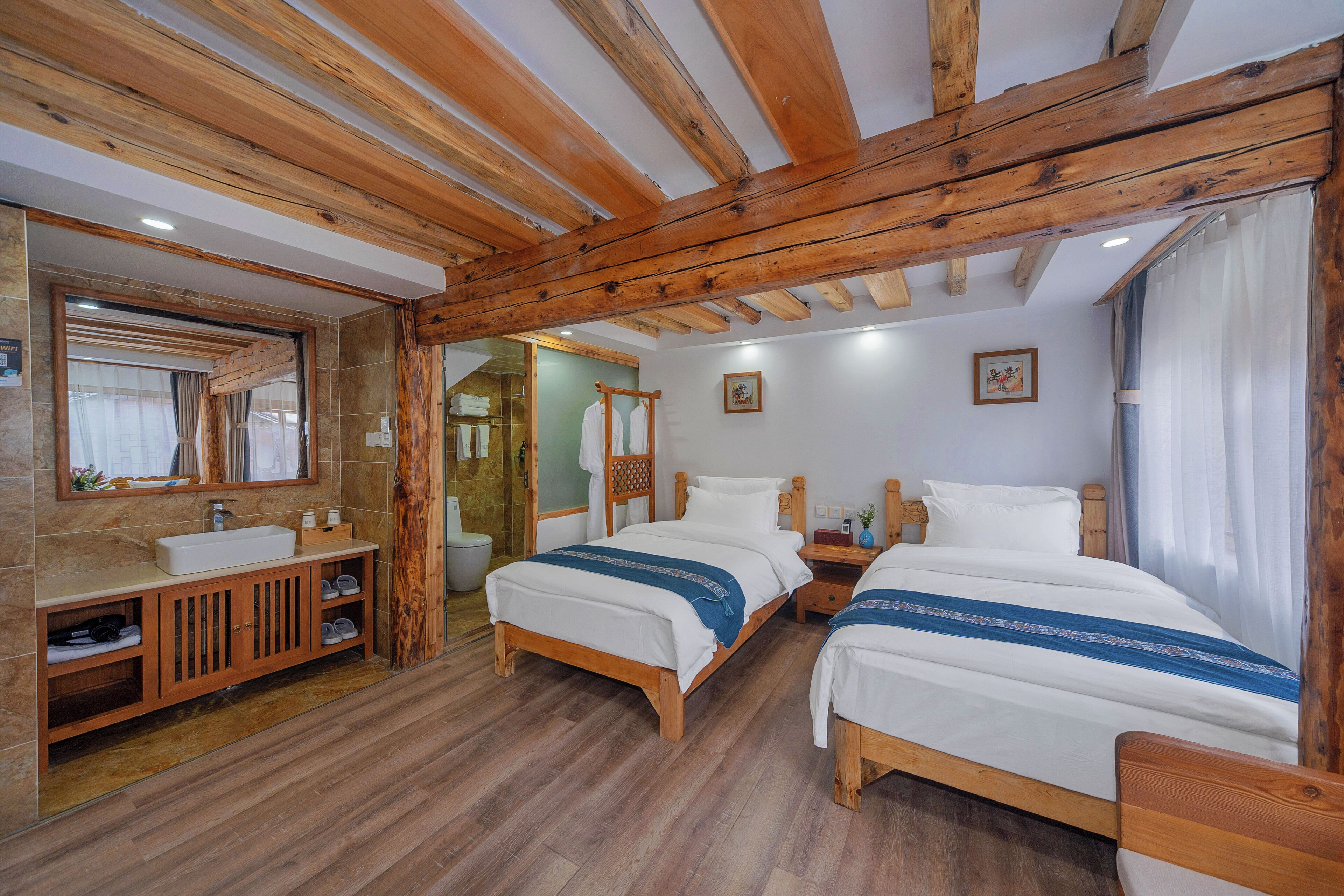 Quarto com duas camas de madeira, uma cômoda de madeira com espelho e banheiro com chuveiro e vaso sanitário.