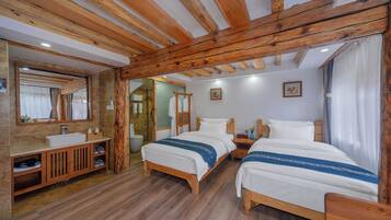 Quarto com duas camas de madeira, uma cômoda de madeira com espelho e banheiro com chuveiro e vaso sanitário.