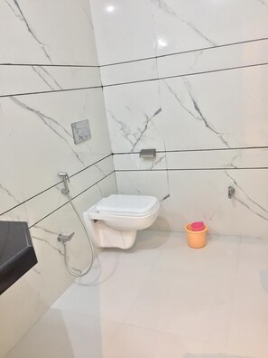 Casa de banho com sanita, chuveiro e lavatório.