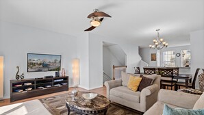 Uma sala de estar moderna com televisão de tela plana, móvel para TV em madeira escura e ventilador de teto.