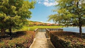 Uma trilha que leva a um edifício, com vista para um lago e um campo de golfe.