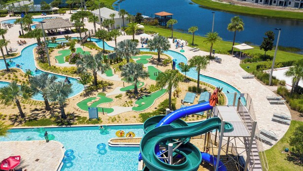 Parque aquático com uma piscina grande, vários toboáguas e uma área de campo de golfe.