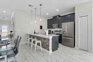 Cozinha moderna com ilha central, eletrodomésticos de aço inoxidável e iluminação pendente.