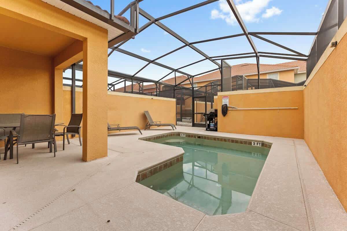 Piscina coberta ao ar livre com teto de vidro, área de estar com cadeiras e uma máquina de café.