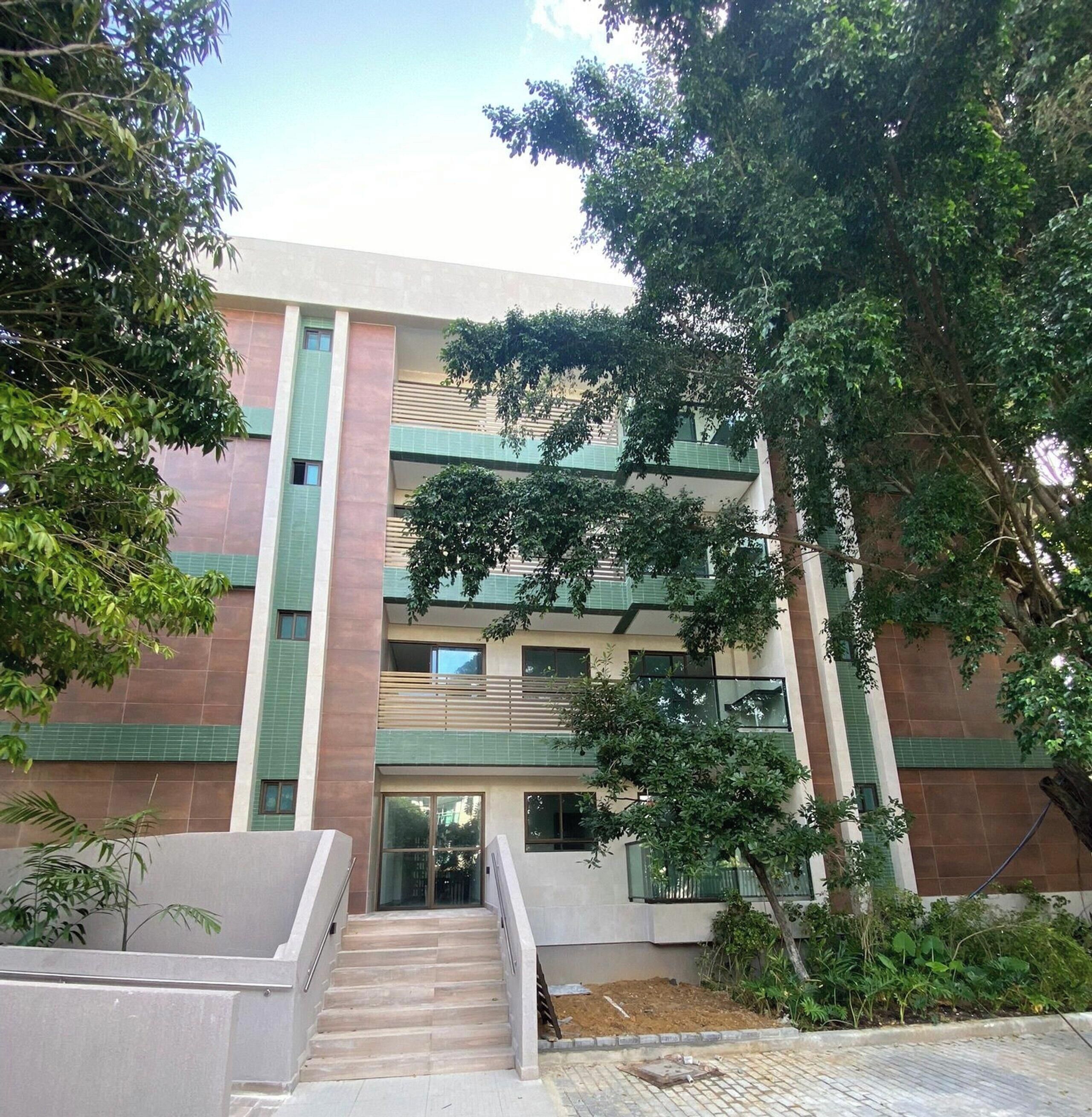 Edifício de vários andares com escadaria central, cercado por vegetação.