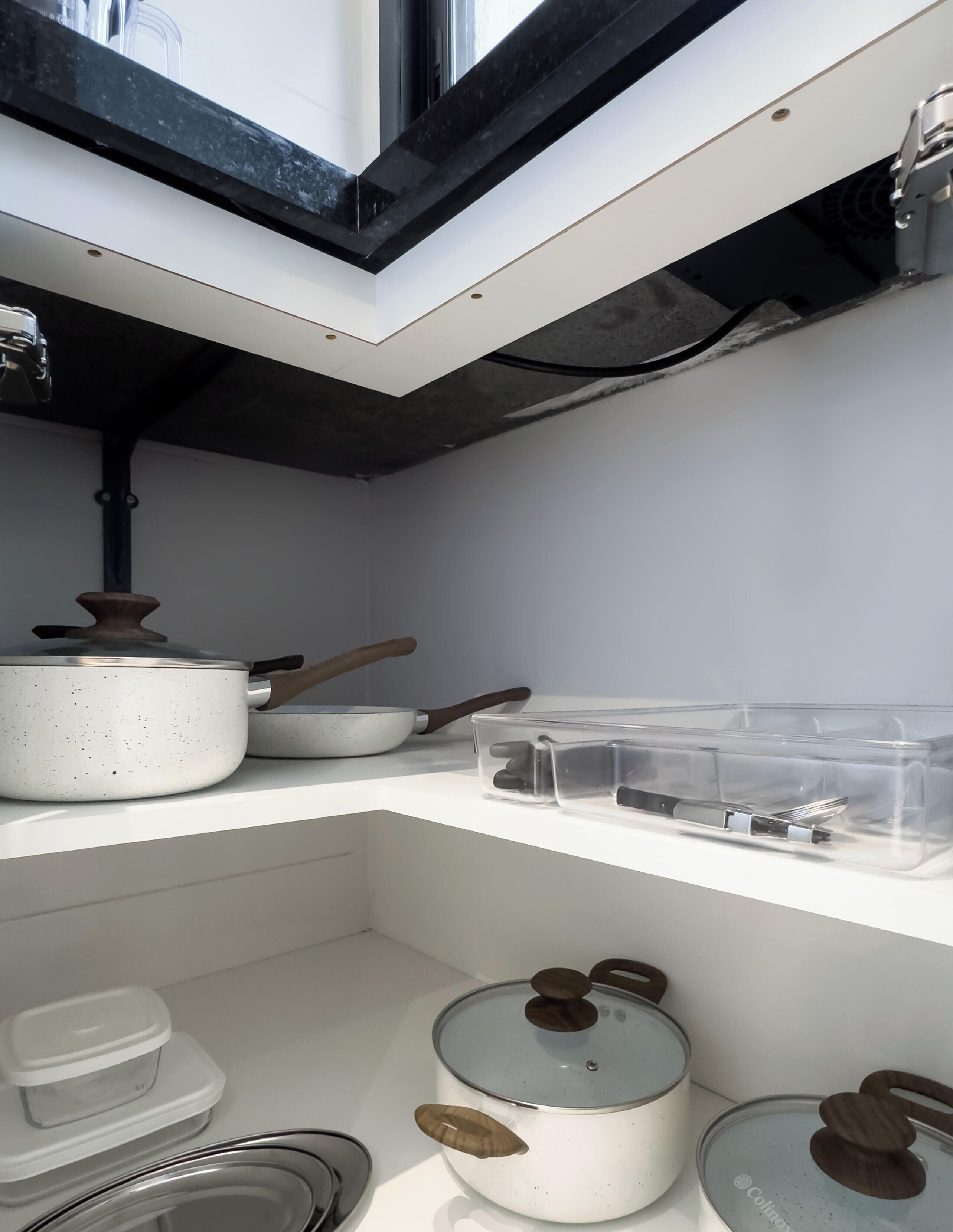 Uma cozinha com armários brancos, uma panela no balcão e uma janela acima.