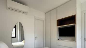 Quarto com cama, espelho, guarda-roupa e prateleira embutida.