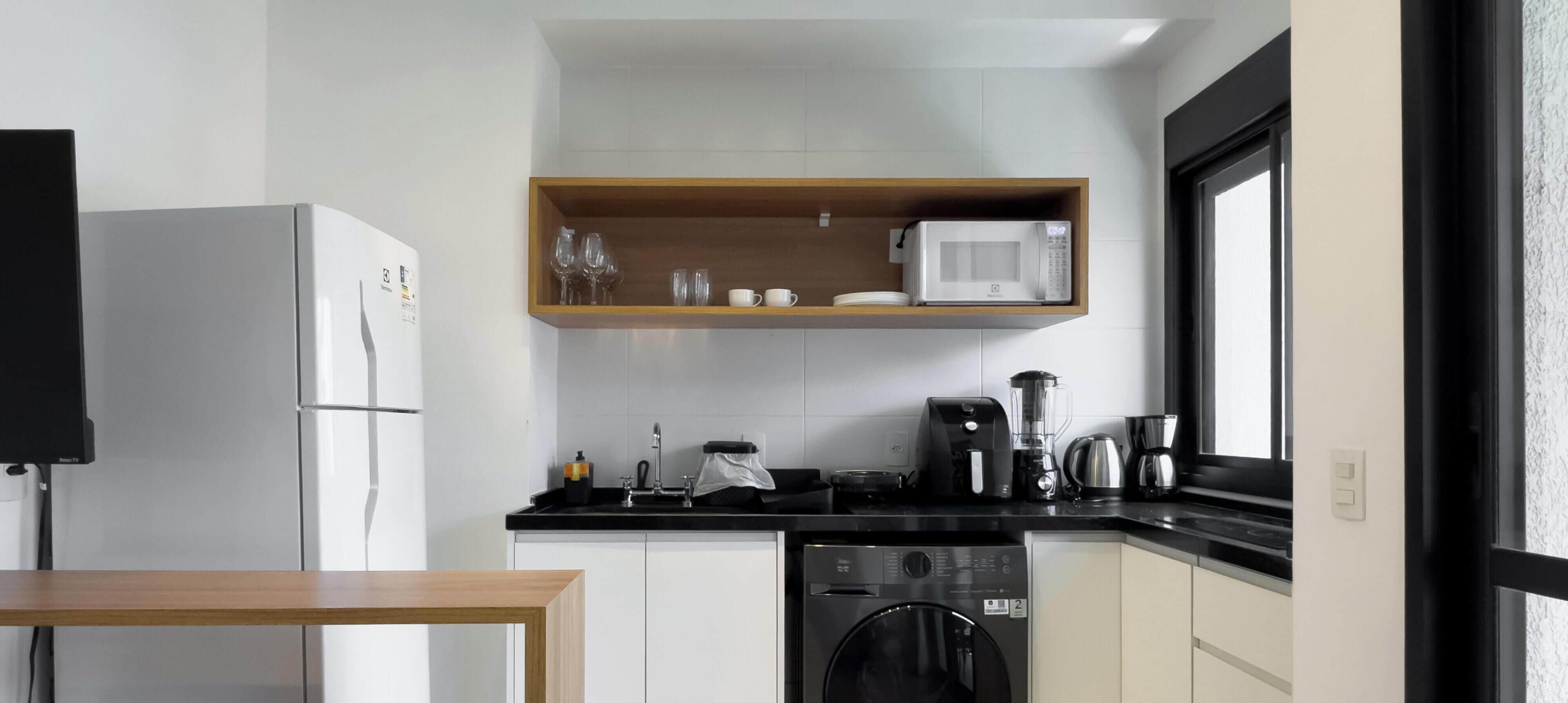 Uma cozinha compacta equipada com geladeira, micro-ondas, cafeteira e lava-louças.