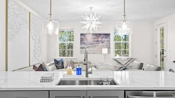 Cozinha moderna com bancada de mármore, eletrodomésticos de aço inoxidável e iluminação pendente.