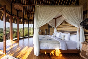 Um quarto espaçoso com uma cama grande, piso de madeira e vista para o exterior.