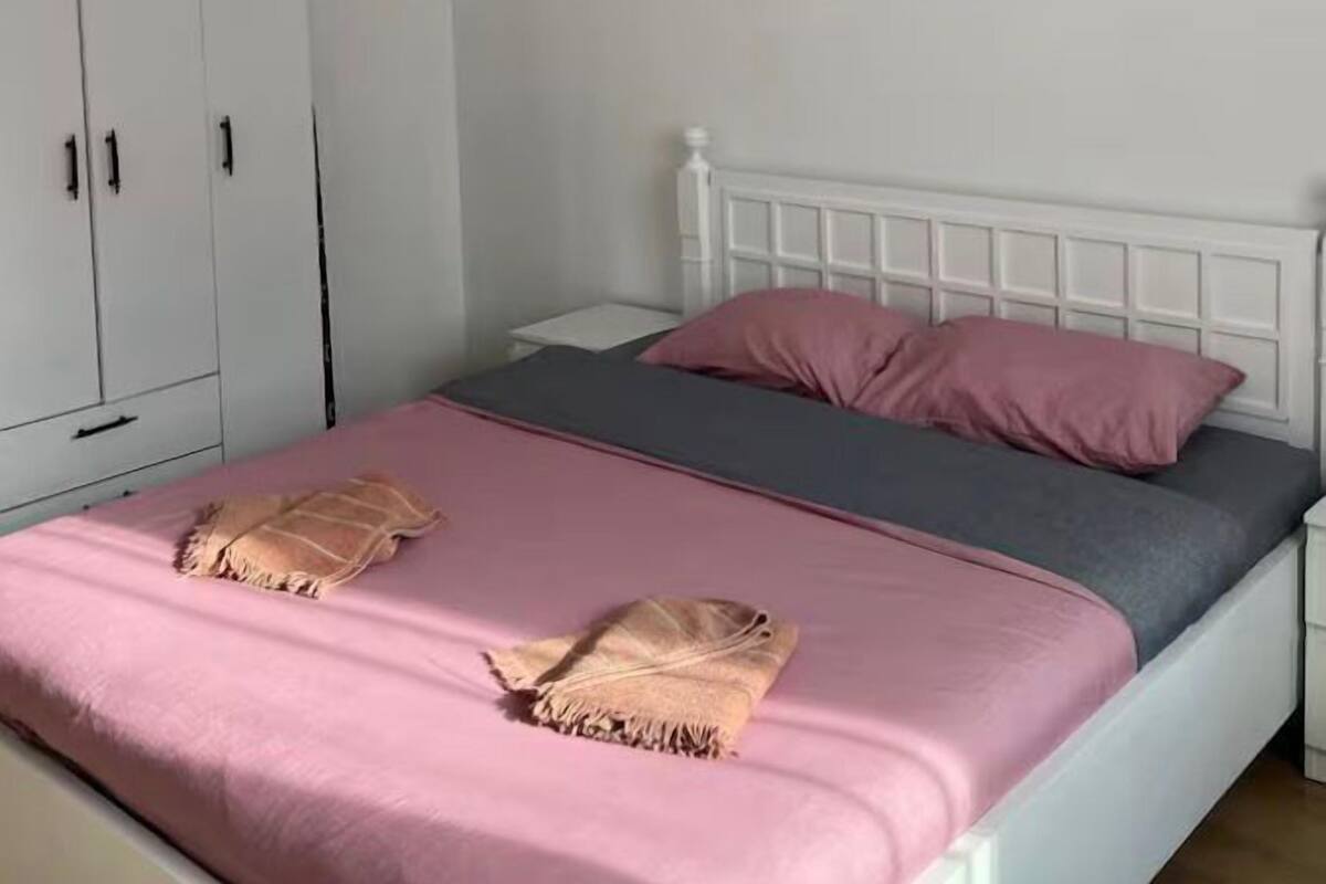 Quarto com cama, ventilador de teto, guarda-roupa e um quadro na parede.