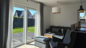 Uma sala de estar moderna com sofá, um banquinho e uma área de jantar com mesa e cadeiras.