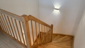 Uma escada de madeira com corrimão e luminária na parede.