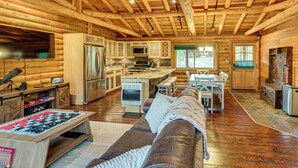 Interior de uma cabana de tronco com cozinha, sala de jantar e sala de estar.