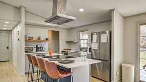 Uma cozinha moderna com ilha central, eletrodomésticos de aço inoxidável e uma lixeira.