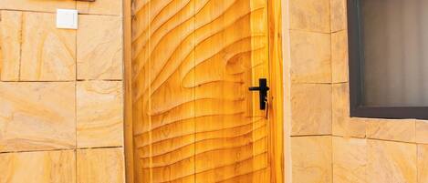 Uma porta de madeira com design único, uma placa com a palavra "Ontome" e uma janela à direita.