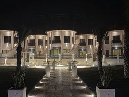Um hotel moderno com vários edifícios interligados, apresentando um pátio central com áreas de estar e um elemento aquático.