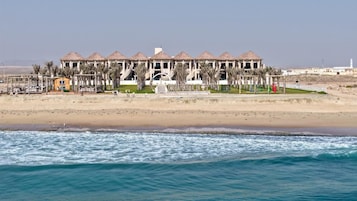 Um hotel à beira-mar com vários edifícios, piscina e palmeiras.