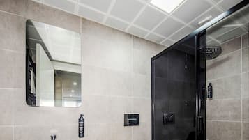 Um banheiro moderno com toucador preto, vaso sanitário branco e chuveiro com divisória de vidro.
