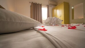 Quarto de hotel com cama, guarda-roupa amarelo e janela com cortinas.