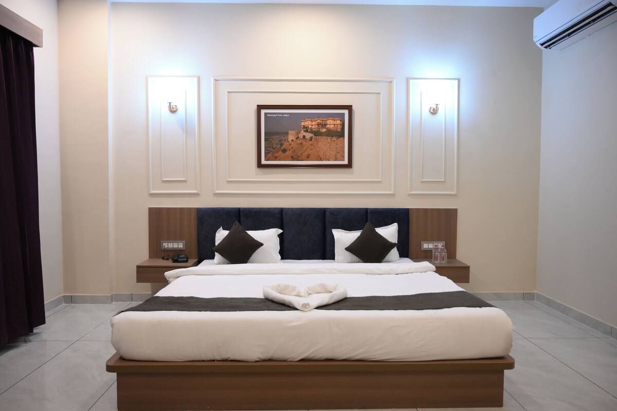 Quarto de hotel bem arrumado, com uma cama grande, um quadro na parede e mesas de cabeceira com luminárias.