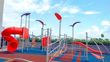 Parque infantil ao ar livre com escorregadores e estruturas de escalada.