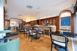 Um saguão de hotel com área de bar, assentos e balcão de recepção.