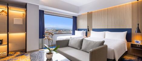 Quarto de hotel com cama, sofá e vista para a cidade.