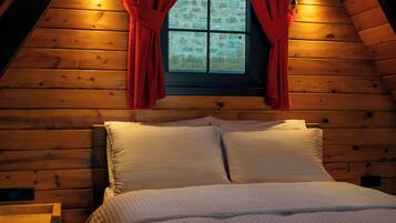 Quarto de cabana de madeira aconchegante, com cama, cortinas vermelhas e janela.