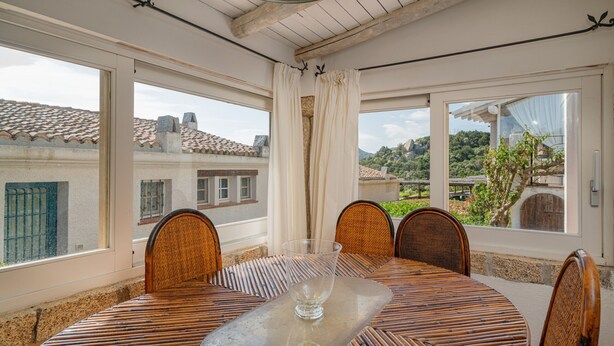 Uma área de refeições com uma mesa redonda, quatro cadeiras de vime e um centro de mesa de vidro.