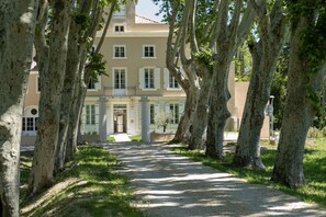 Uma trilha leva a um edifício de estilo arquitetônico clássico, cercado por árvores.