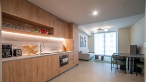 Uma cozinha moderna com armários de madeira, forno embutido e um espaço de refeições com mesa e cadeiras.