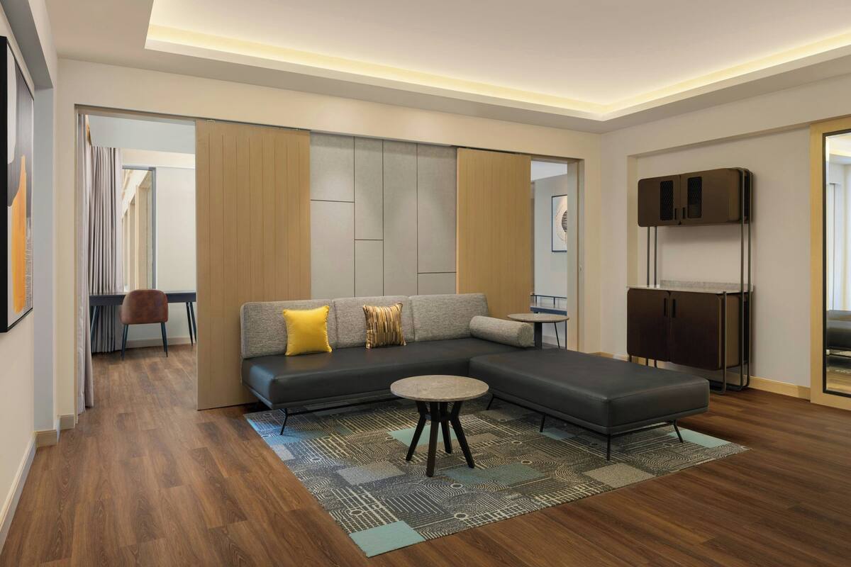 Uma sala de estar moderna com um sofá seccional, uma mesa de centro redonda e um tapete estampado.