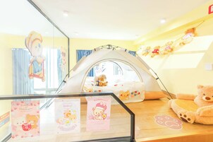 Um quarto com uma estrutura tipo tenda, um urso de pelúcia e livros infantis na mesa.