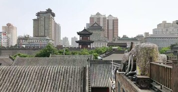 Um edifício tradicional com telhado em telhas e uma estrutura em estilo pagode ao fundo.