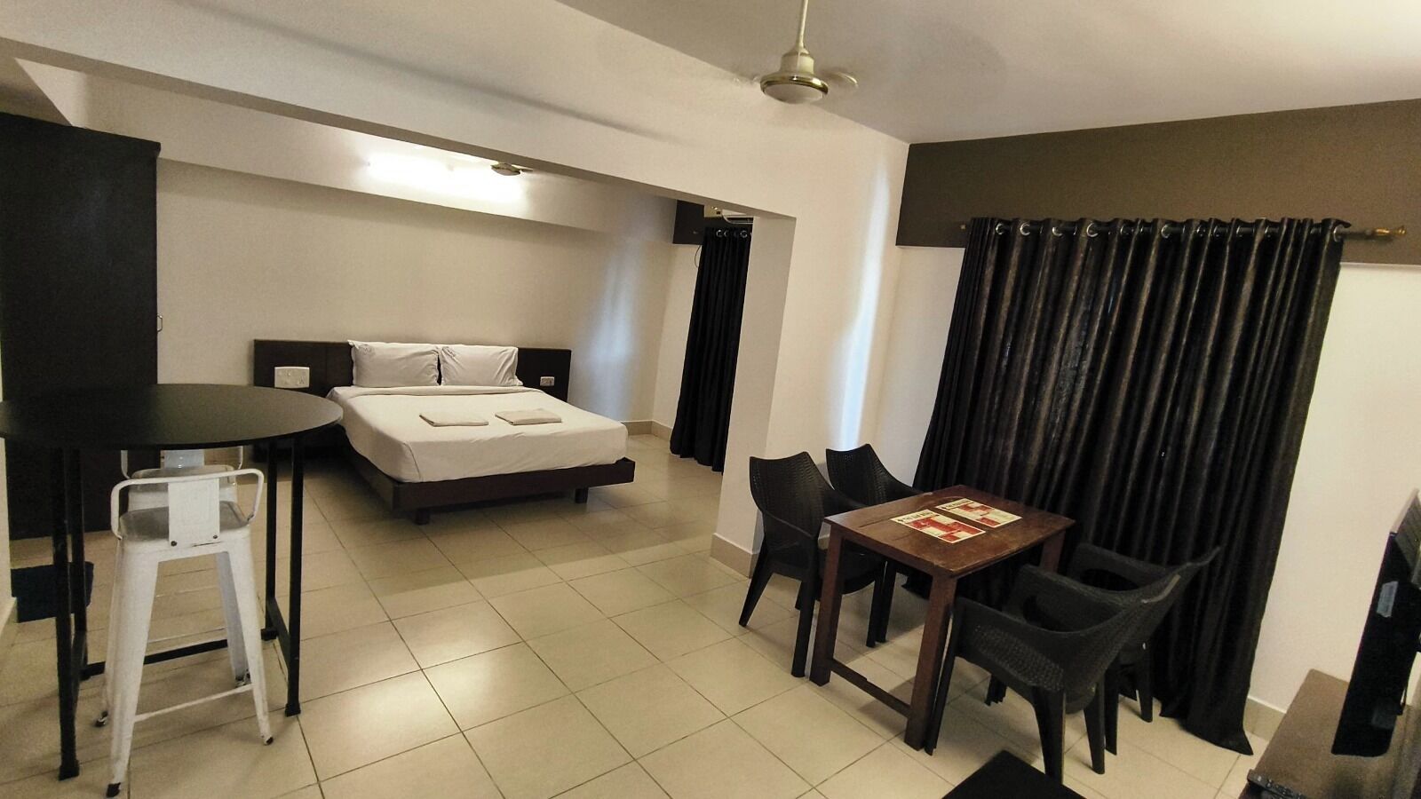 Quarto de hotel pequeno com uma cama, uma mesa de jantar, uma cadeira, um sofá e uma televisão.
