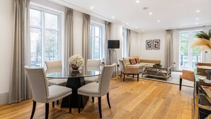 Uma sala de estar espaçosa com área de jantar, janelas amplas e design de interiores moderno.