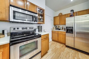 Uma cozinha com armários de madeira, eletrodomésticos de aço inoxidável, micro-ondas, forno e geladeira.