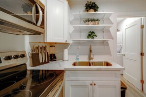 Uma cozinha moderna com armários brancos, eletrodomésticos de aço inoxidável e forno embutido.