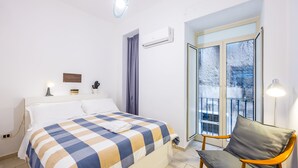 Quarto com cama, cadeira, janela e ar condicionado.