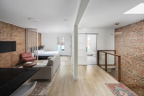 Uma sala de estar moderna com uma parede de tijolos, um sofá, uma TV e uma escadaria.