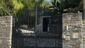 Uma entrada murada com parede de pedra e portão de metal.
