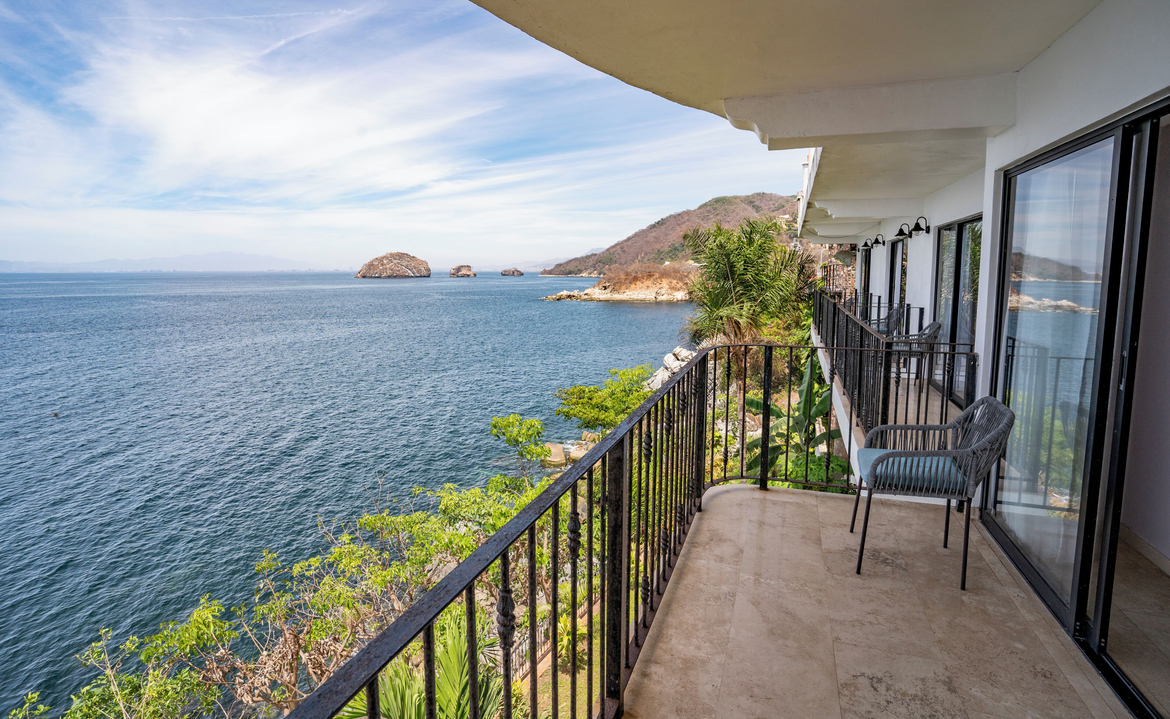 Uma varanda com vista para o mar, uma cadeira e uma mesa.